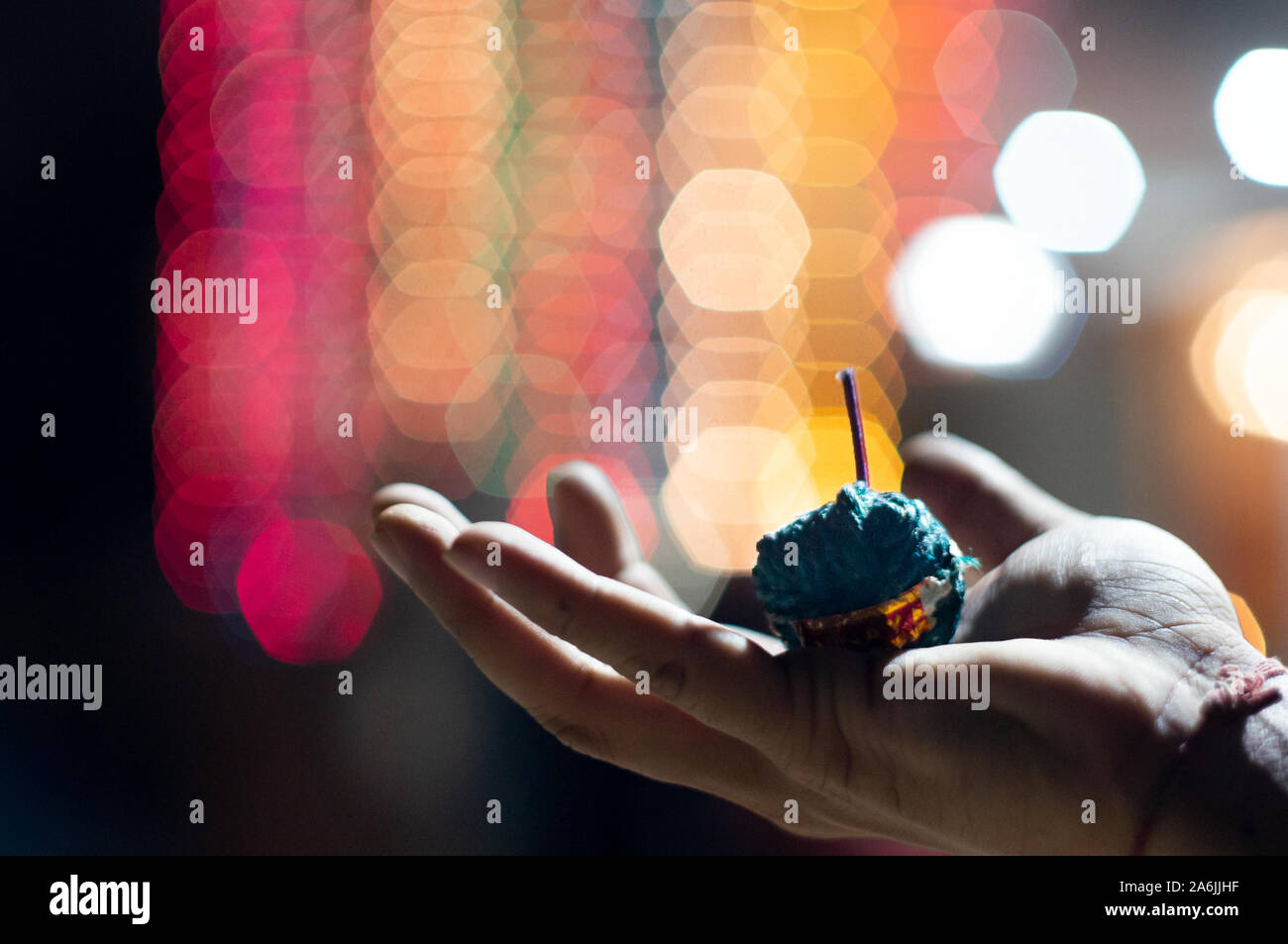 Human hand holding green sutli rassi bomb in front of out of focus ...