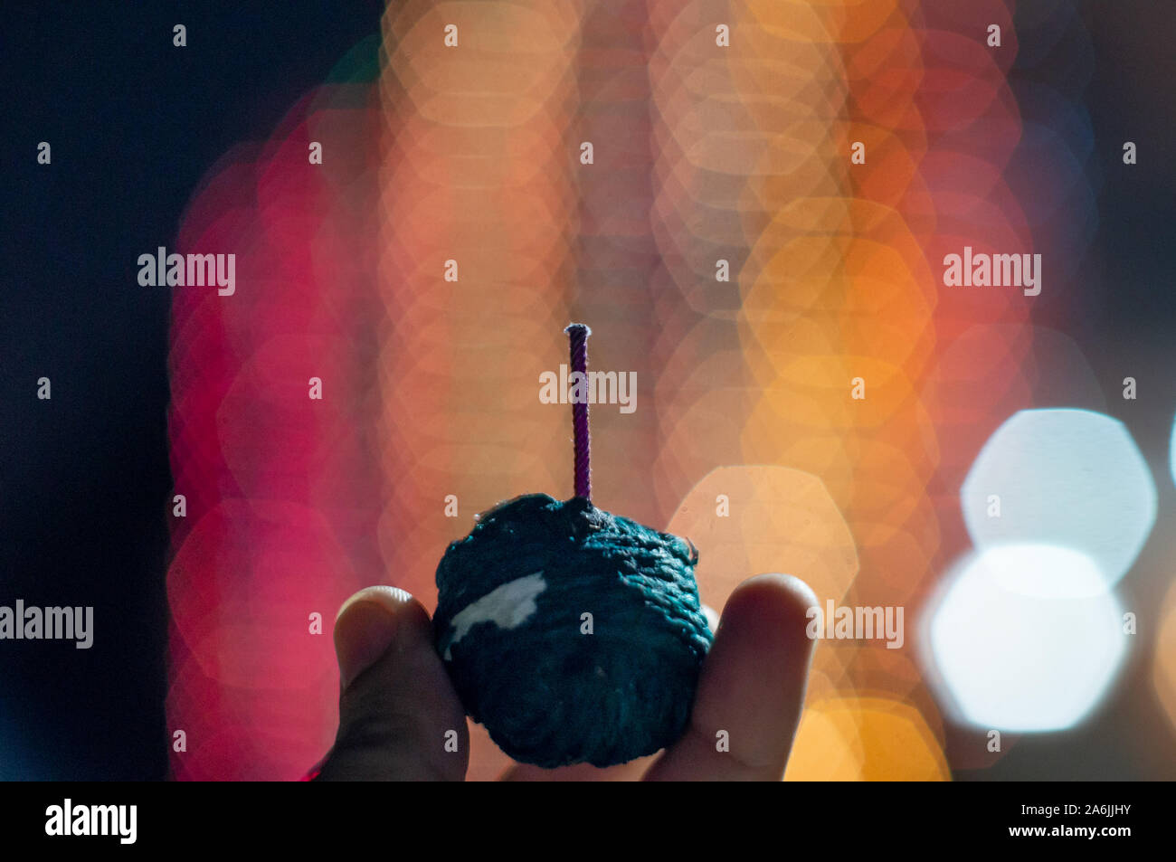 Human hand holding green sutli rassi bomb in front of out of focus ...