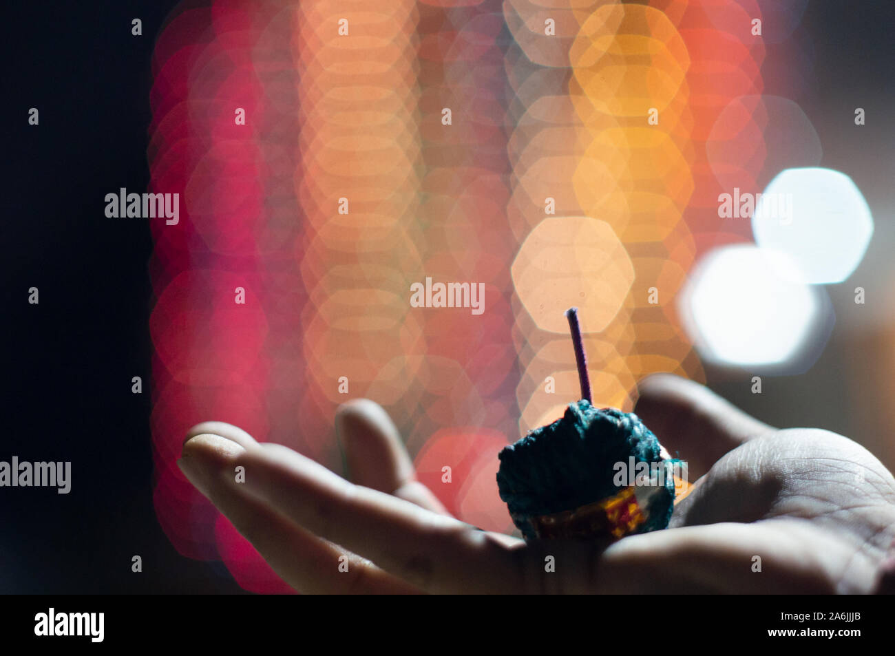 Human hand holding green sutli rassi bomb in front of out of focus ...