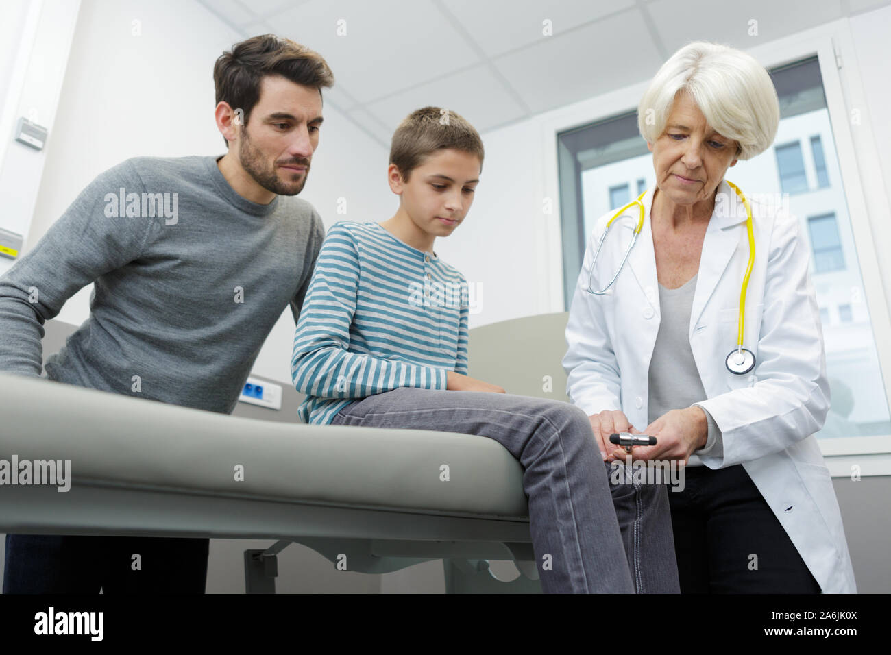 senior female therapist examining boy with reflex hammer Stock Photo ...
