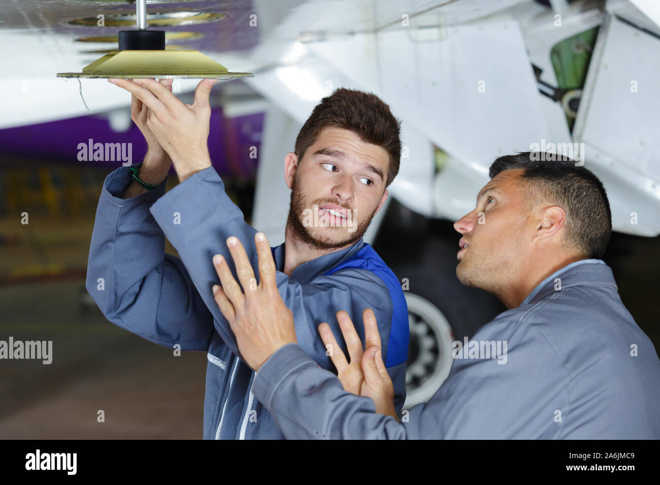 trainee working underneath aircraft under supervision Stock Photo - Alamy