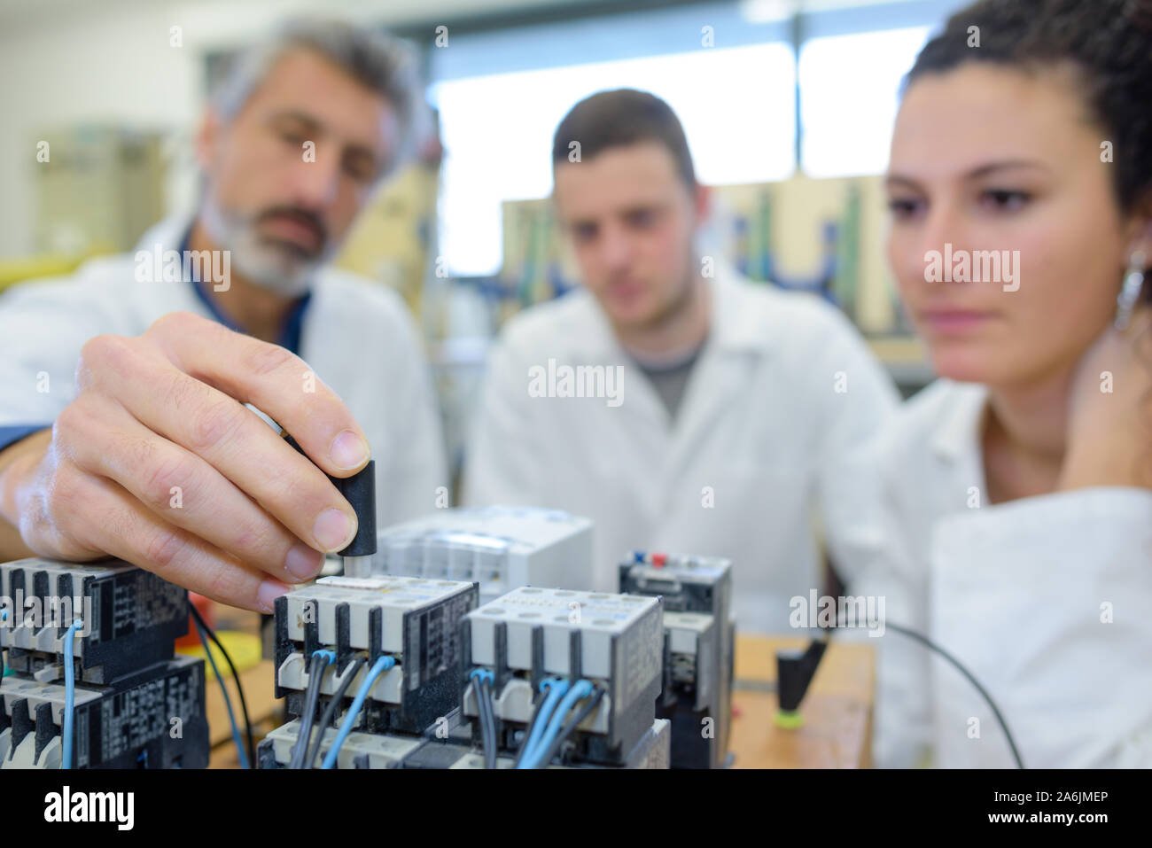 teacher connecting electronics circuit as students look on Stock Photo ...