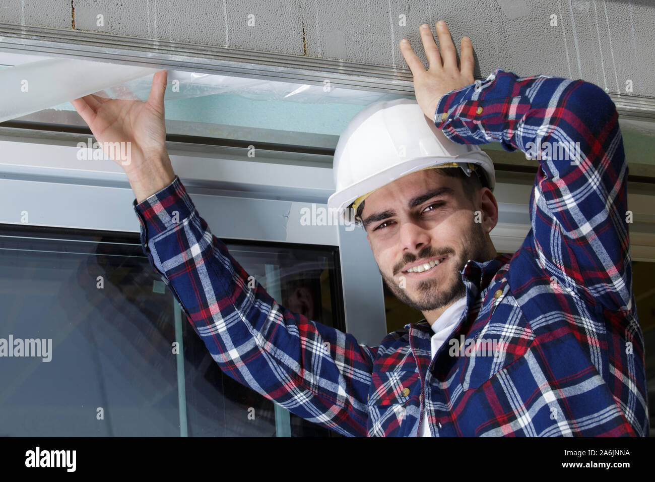 portrait of a builder holding up a window facia Stock Photo - Alamy
