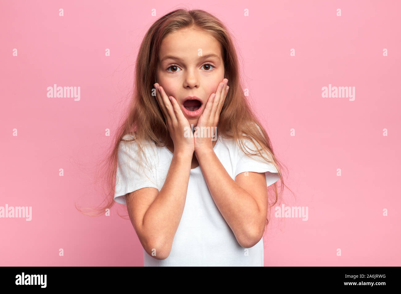 Close up portrait of surprised child with hand on face. Little girl ...