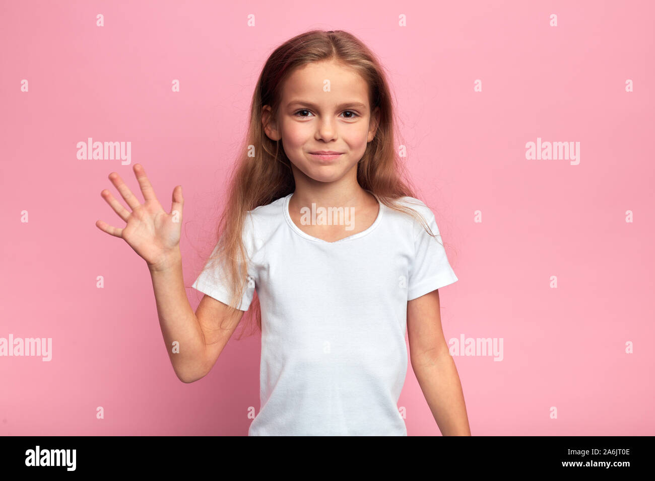 little smiling beautiful girl in white T-shirt waving her hand, saying ...