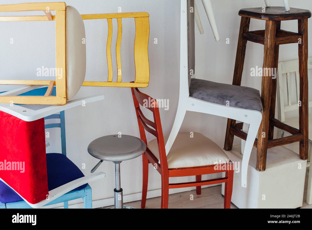many different chairs of different colors stand at the white wall Stock ...