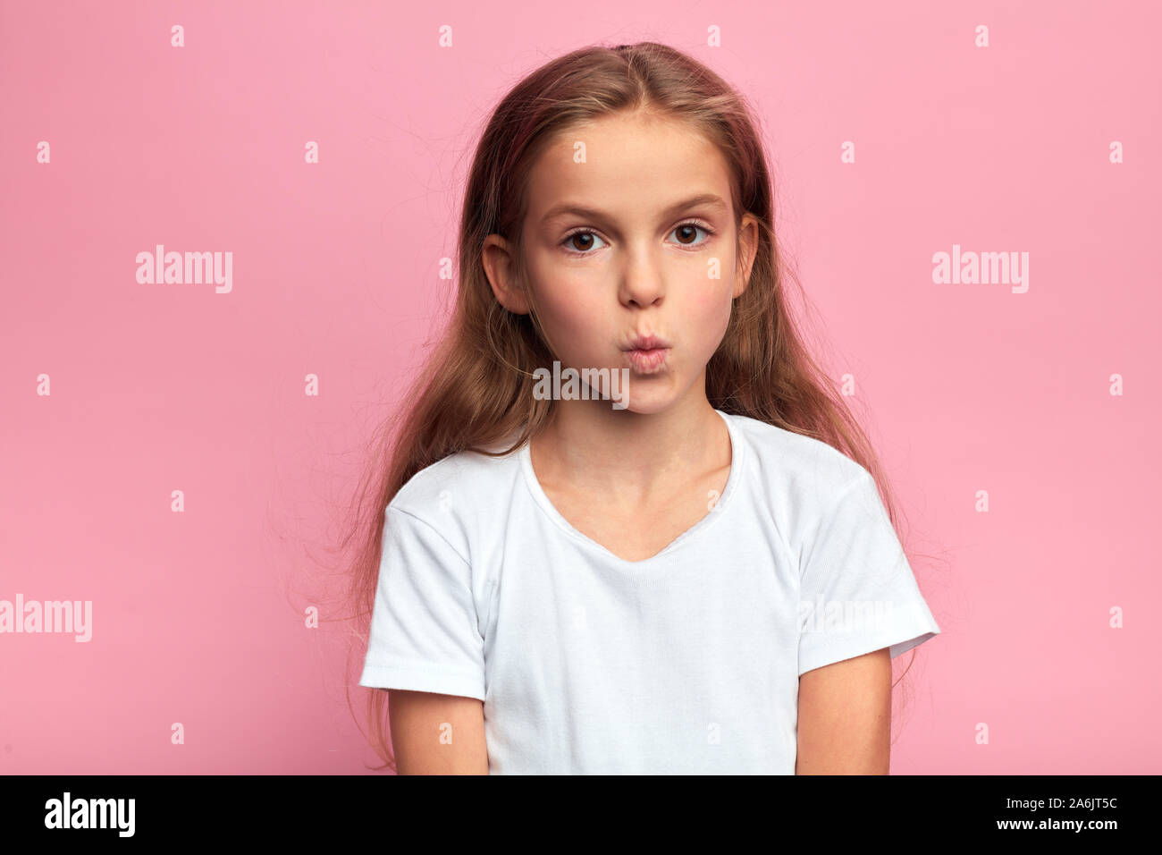 closeup portrait of serious little kid in white t-shirt with pursed ...