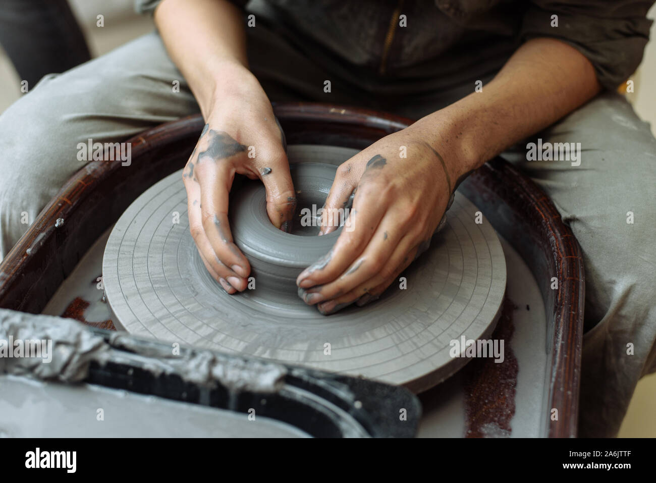 The girl sits at the Potter's wheel and creates a pot of ceramics. A ...