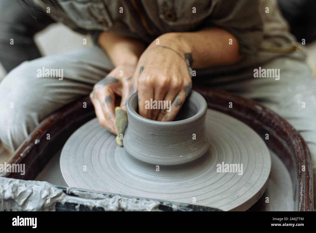 The girl sits at the Potter's wheel and creates a pot of ceramics. A ...