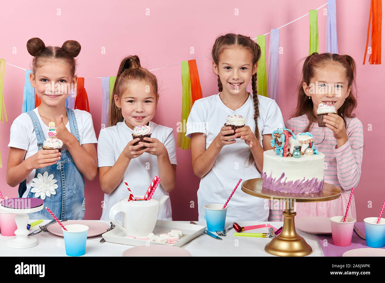 Happy little children eat cupcakes. isolated pink background, studio ...