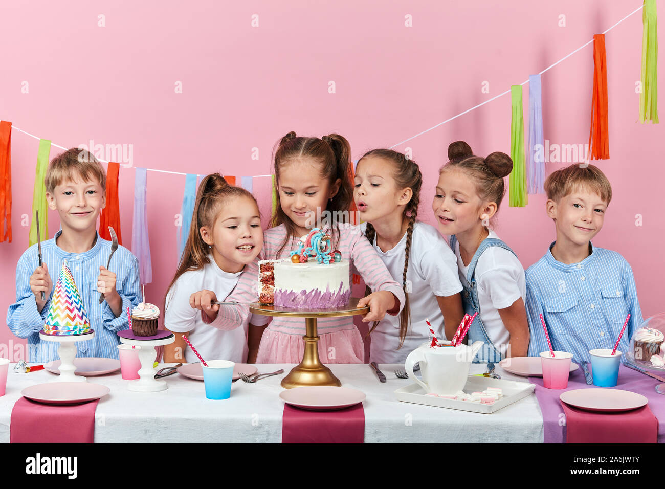beautiful girl sharing cake among her friends. isolated pink background ...