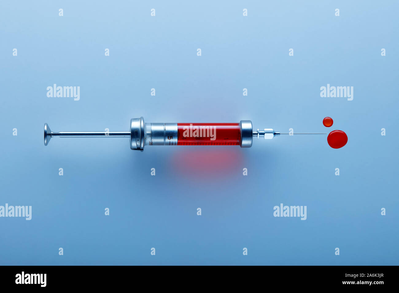 Vintage syringe filled with blood and blood sample drops on blue ...