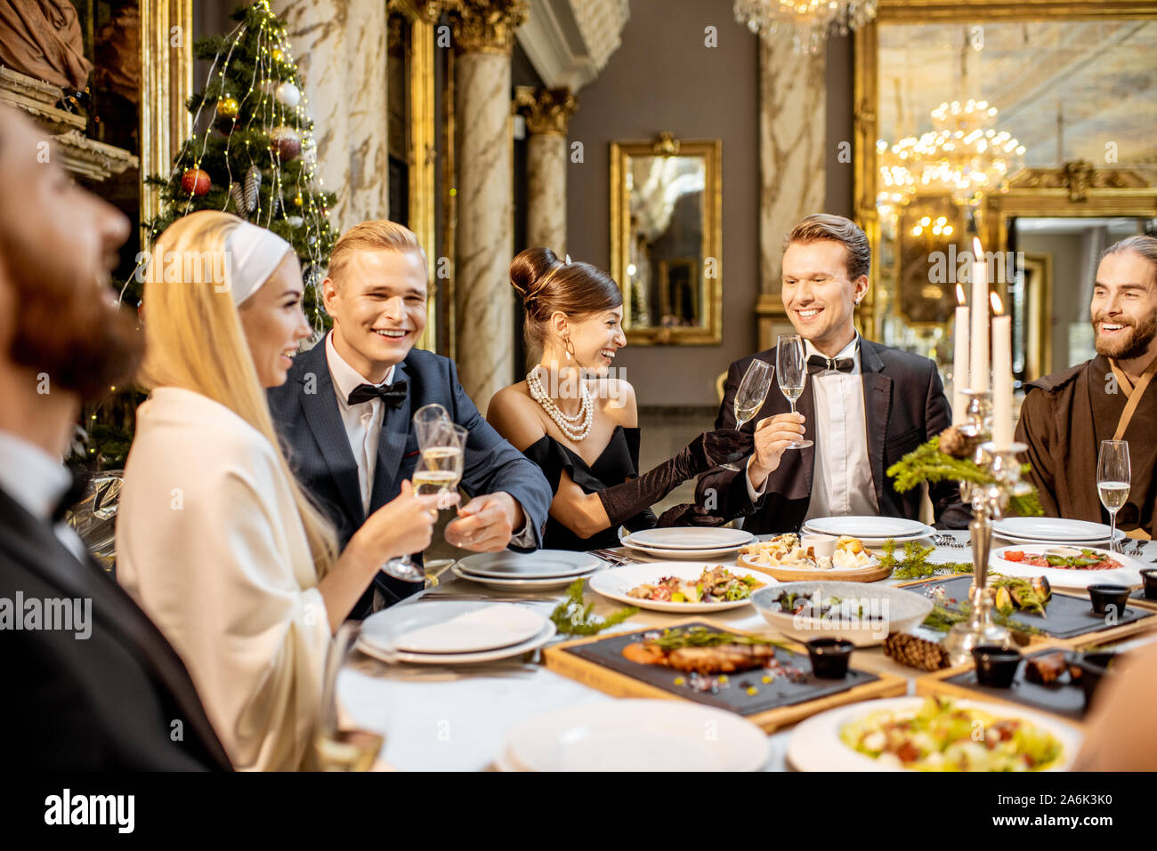 Elegantly dressed group of people having a festive dinner at a well ...