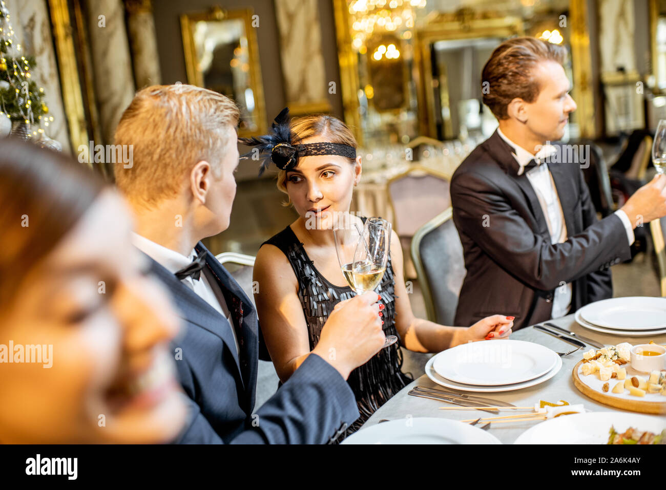 Elegantly dressed group of people having a festive dinner at a well ...