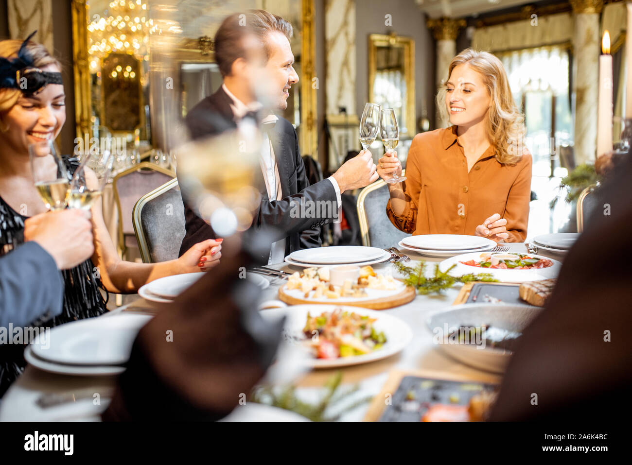 Elegantly dressed group of people having a festive dinner at a well ...
