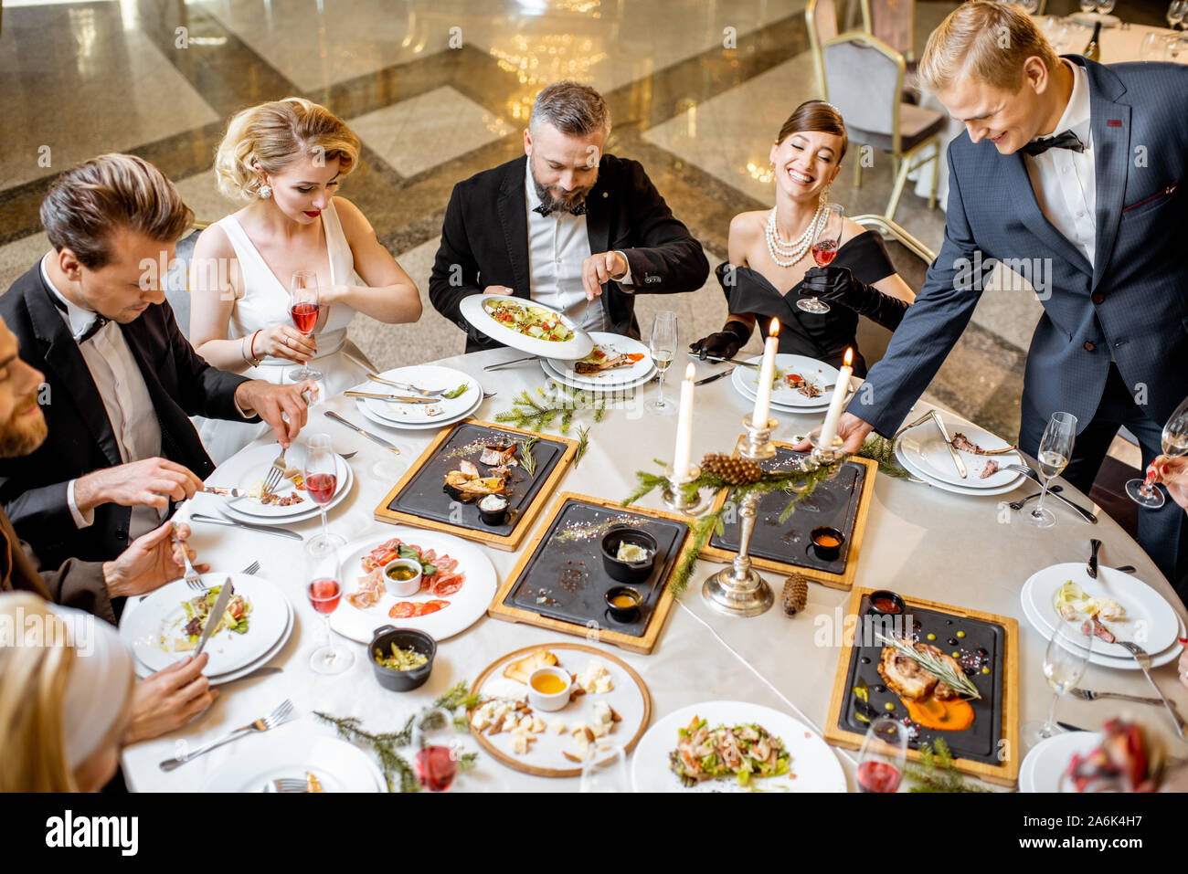 Elegantly dressed group of people having a festive dinner at a well ...