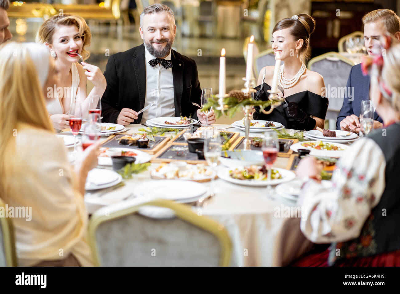 Elegantly dressed group of people having a festive dinner at a well ...
