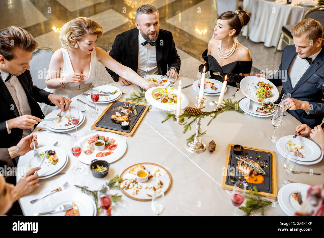 Elegantly dressed group of people having a festive dinner at a well ...