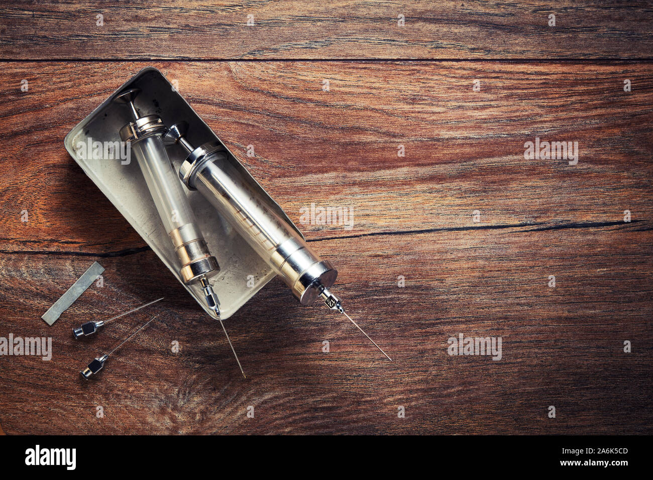 Vintage glass syringe in a metal box and needles on wooden table ...