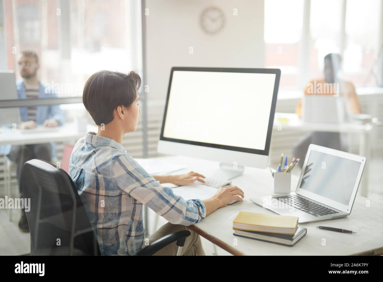 Side view portrait of modern young woman using computer in office ...