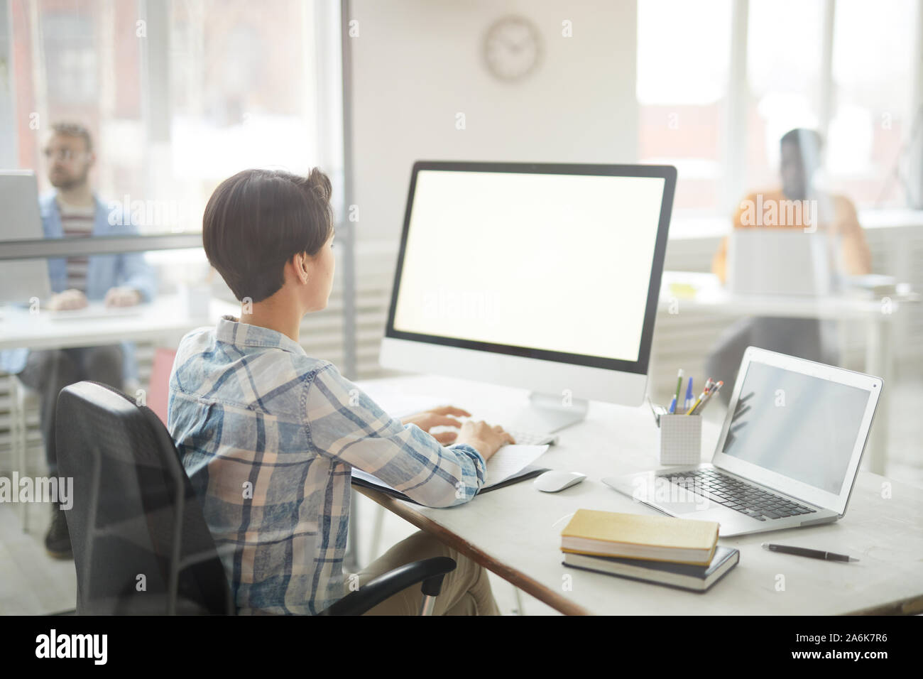 Back view portrait of modern young woman using computer in office ...