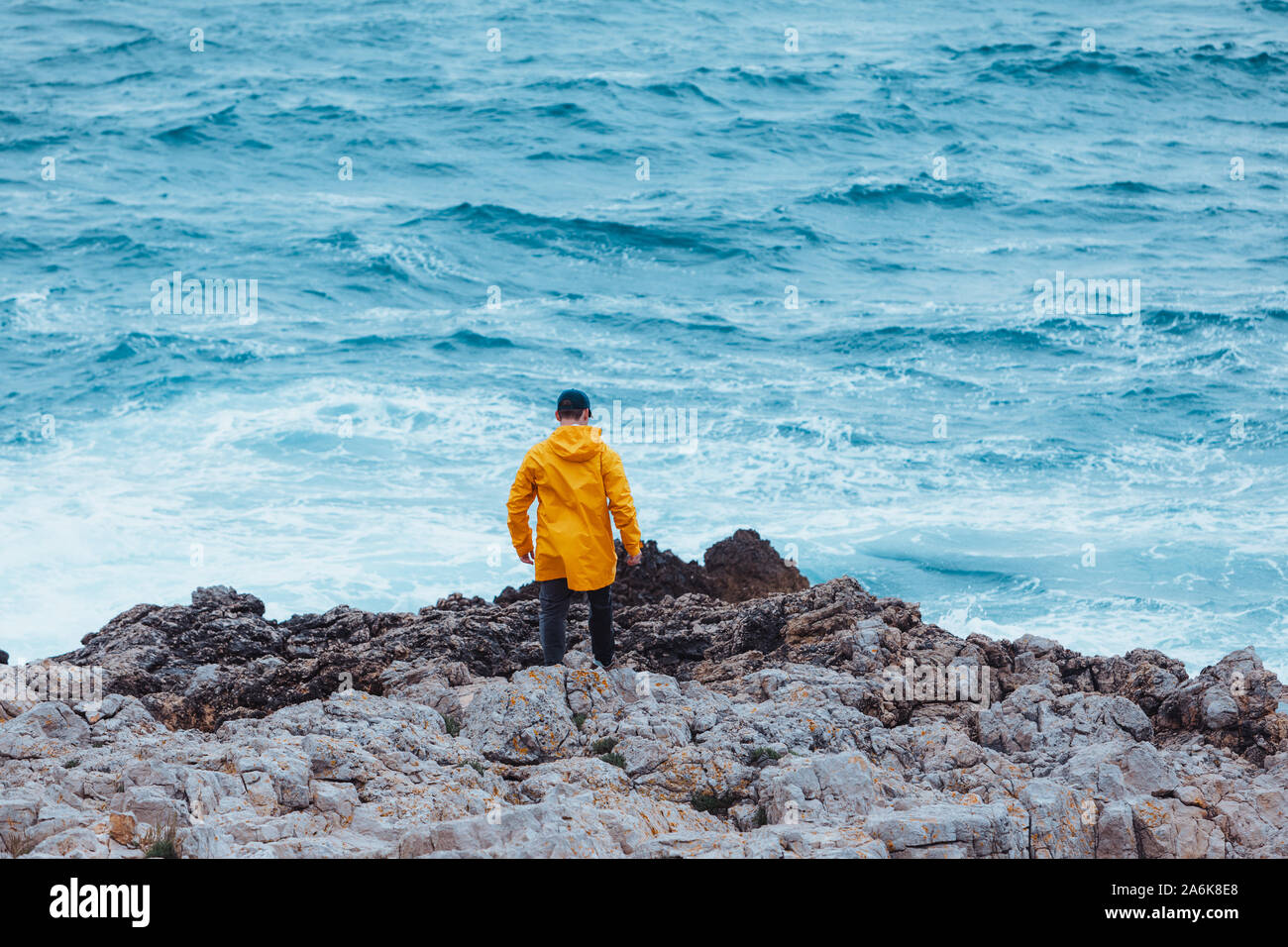 man walking by rock to storming sea Stock Photo - Alamy
