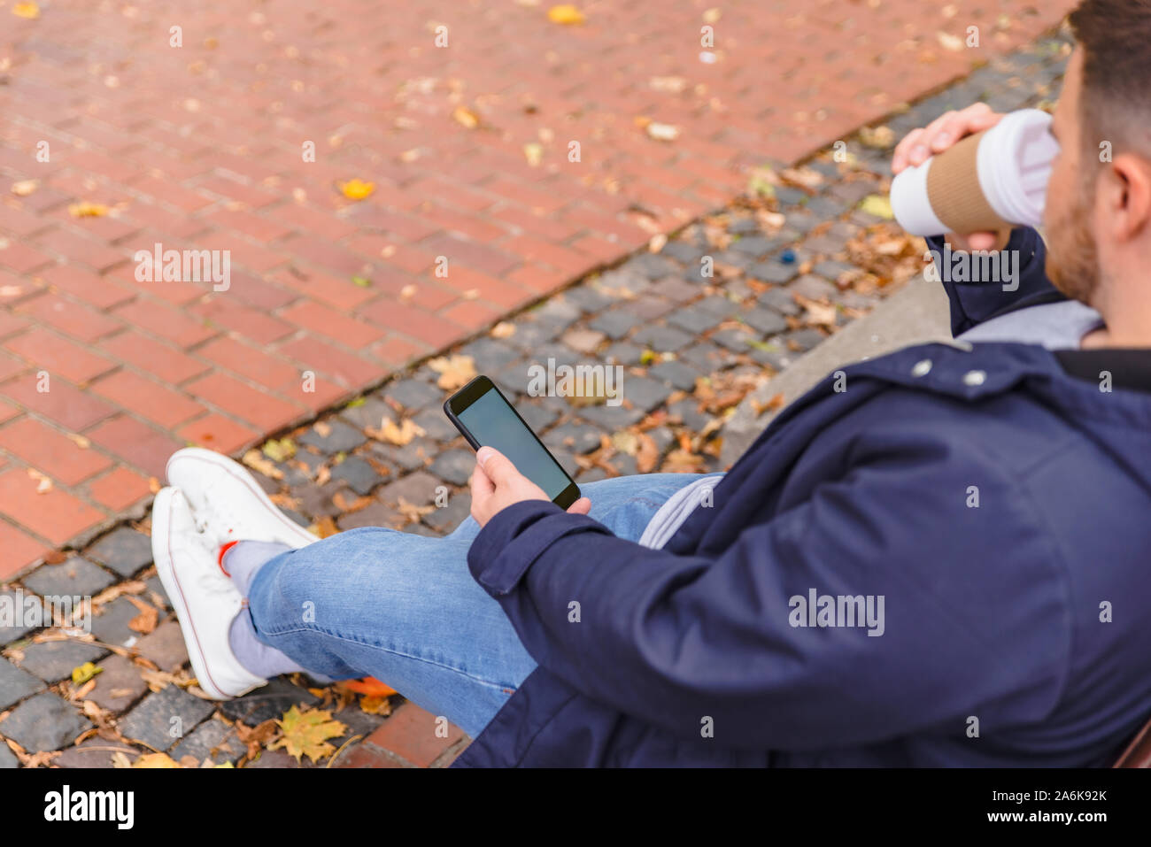 no face man sitting on the bench at city park drinking coffee surfing ...