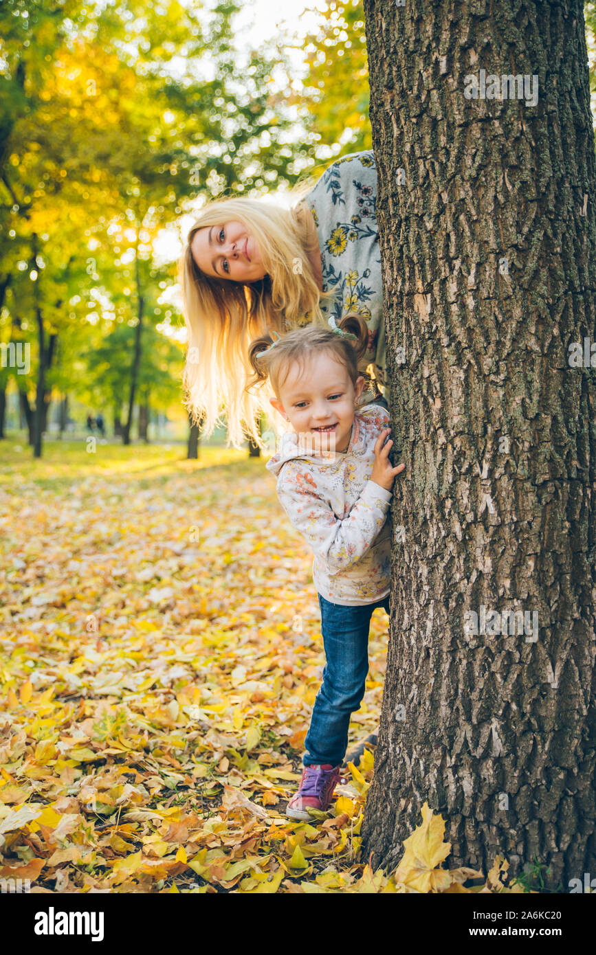 mother with daughter peeps out of the tree Stock Photo - Alamy