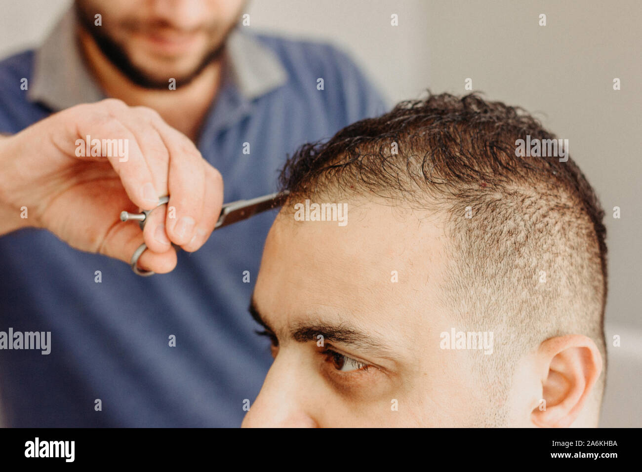 Barber making stylish haircut with professional scissers in barber shop ...