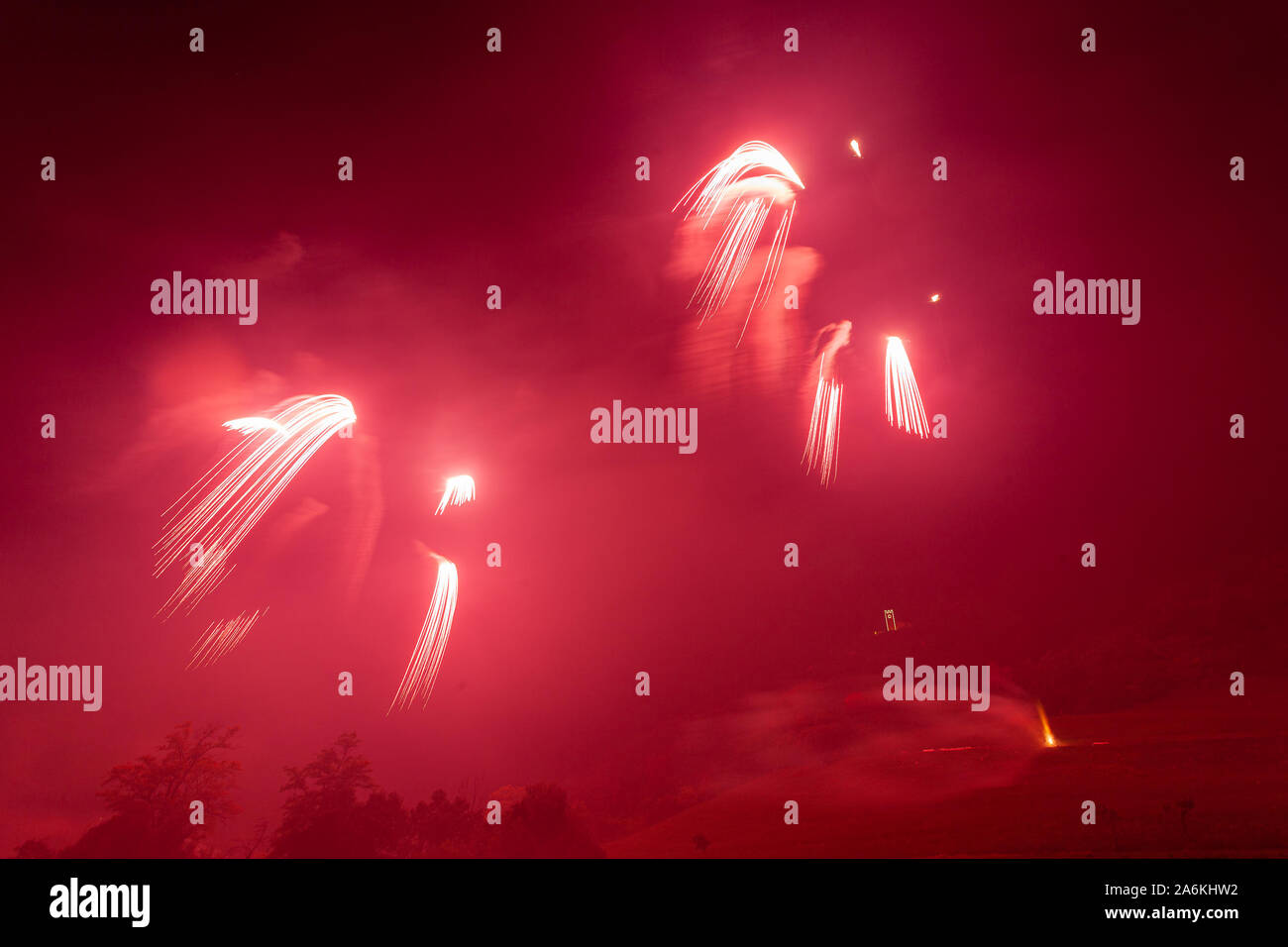 Bright red fireworks with wake effect over trees silhouette Stock Photo ...