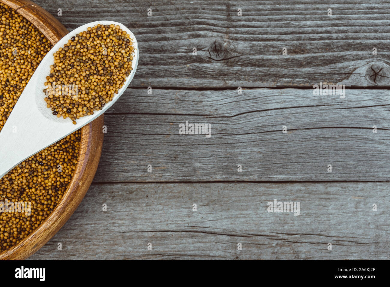 Mustard seeds in wooden plate with spoon on table. Cooking porridge ...