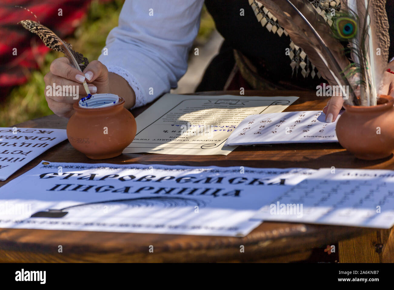 Woman writing a letter with a feather in ourdoors setting. Ancient ...