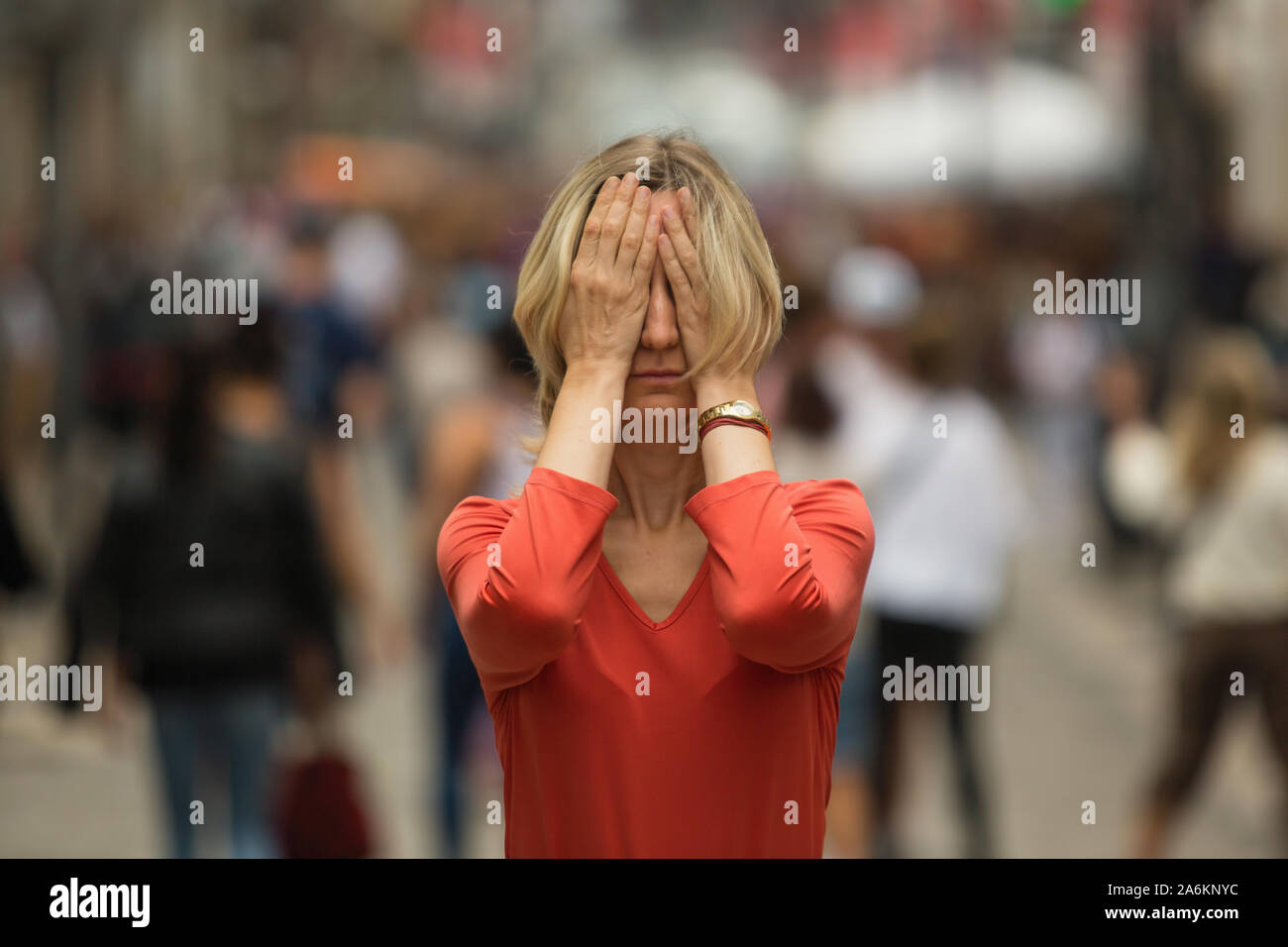 Panic attack on the street. Female covers her face with her hands as ...