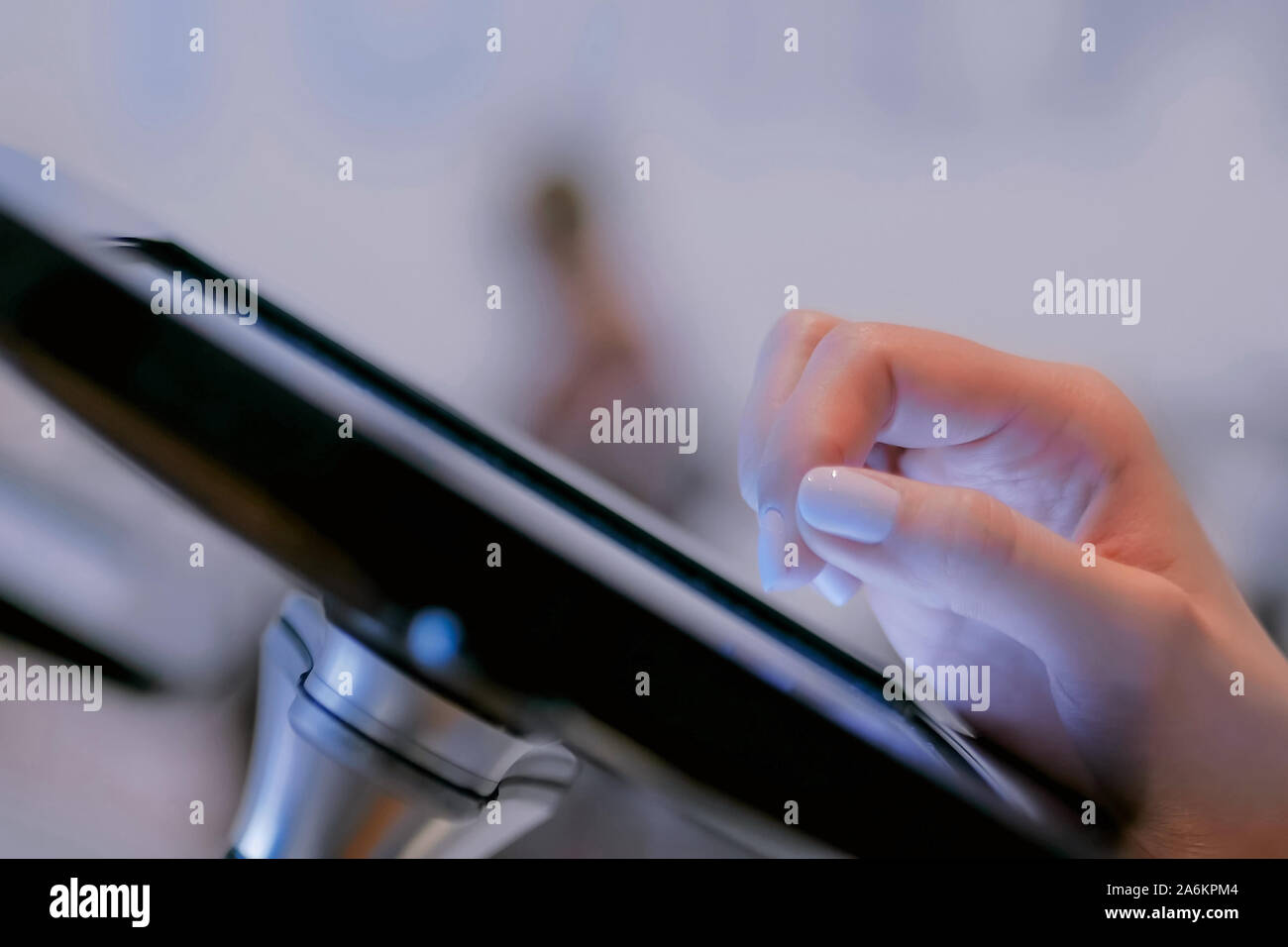 Woman hand using touchscreen display of floor standing black tablet ...