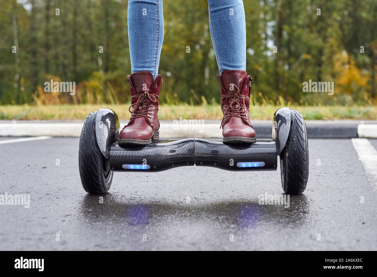 Woman using hoverboard on asphalt road, close up. Feet on electrical ...