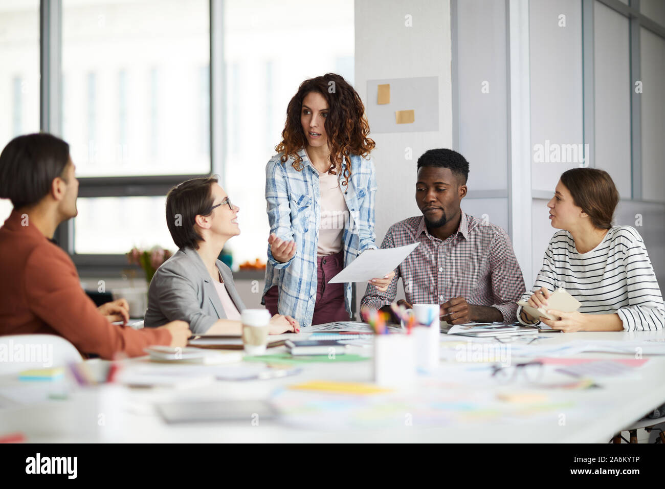 Diverse group of business people sharing ideas while sitting at table ...