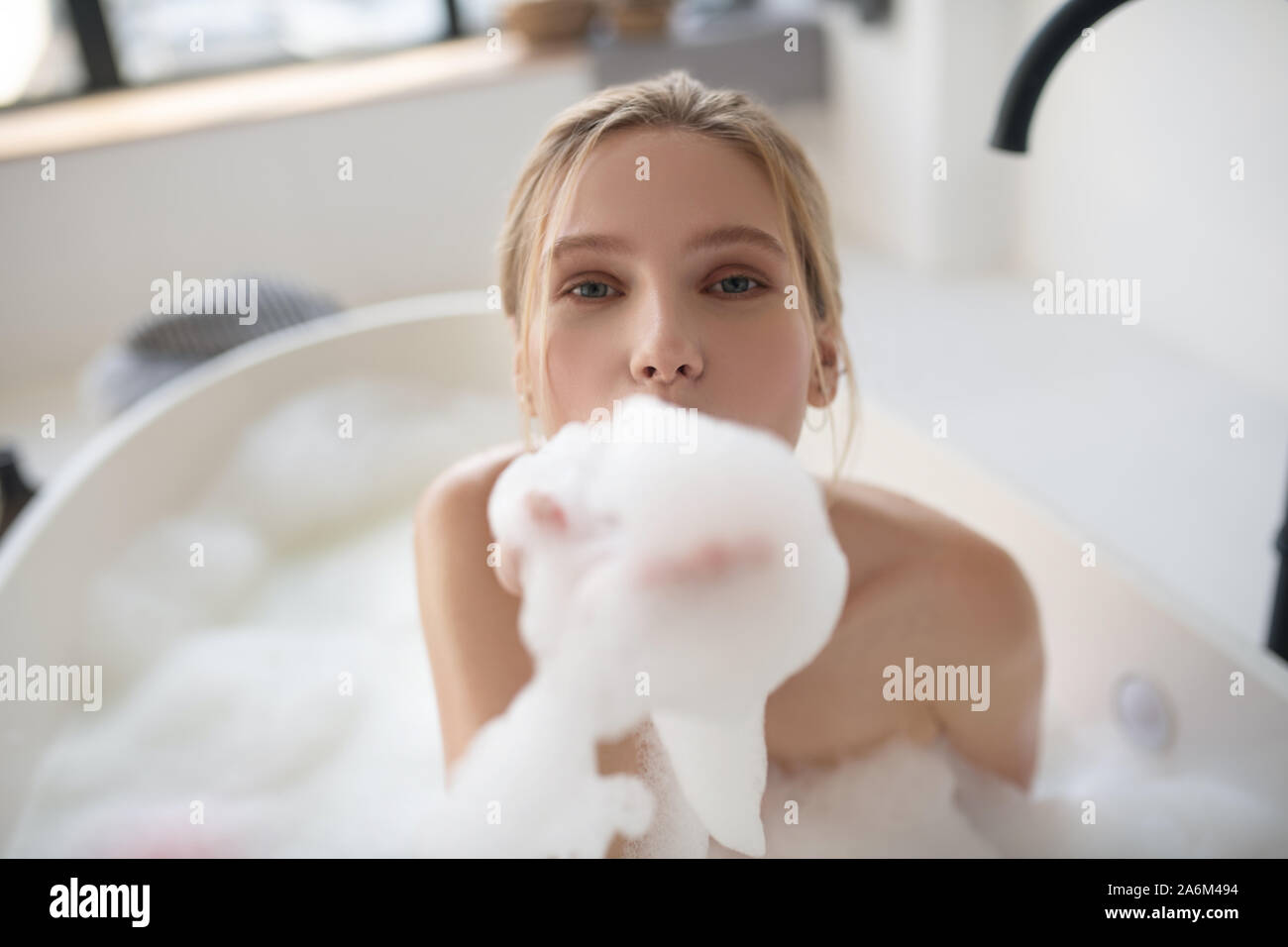 Blue-eyed woman holding foam in her hands while having bath Stock Photo ...