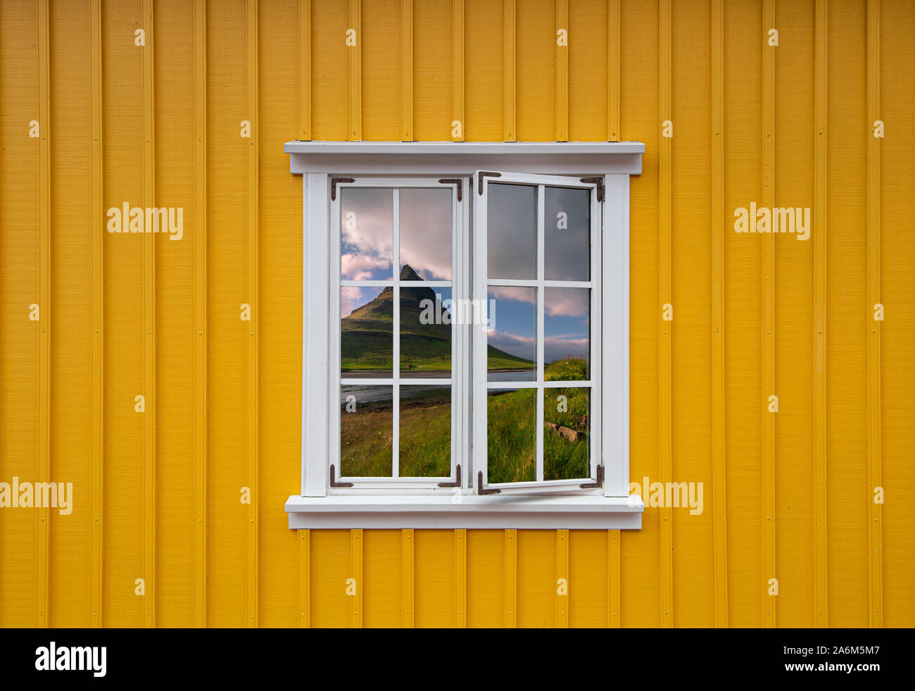 Yellow wooden house with a white window with a reflection of the ...