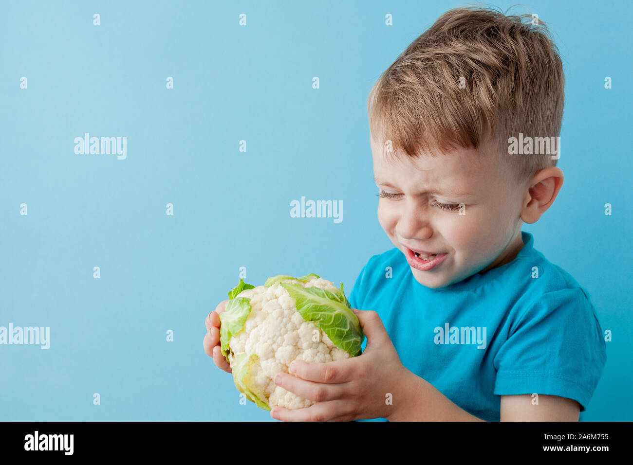 Little Boy Holding Broccoli in his hands on blue background, diet and ...