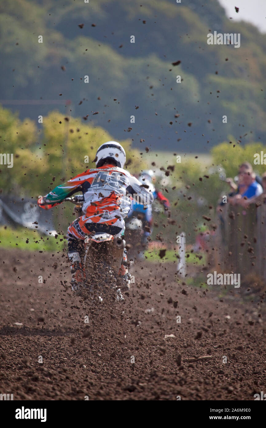 View of back of motocross riders with mud flying up in the air, England ...