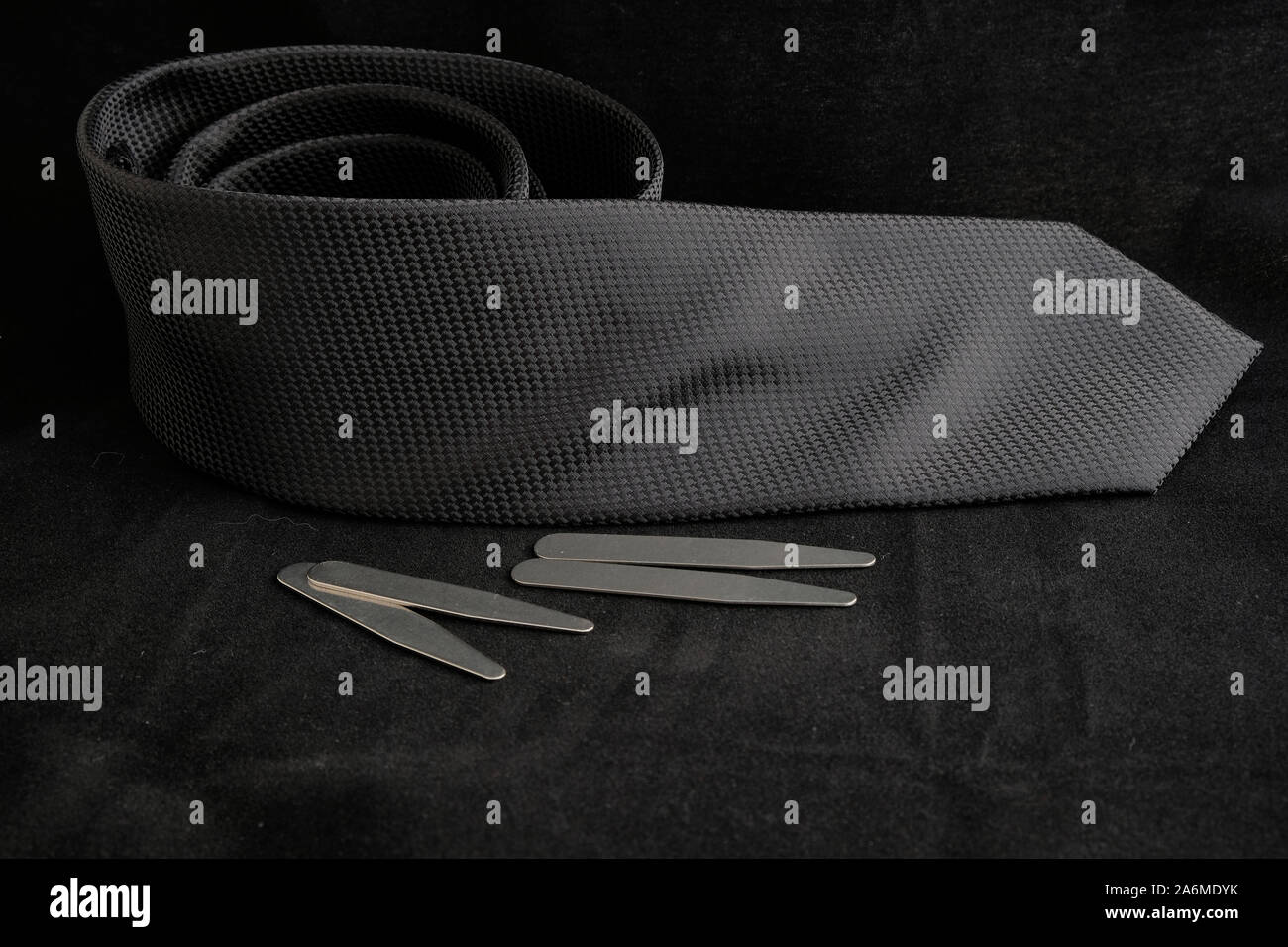 Rolled up neck tie with two pairs of metal collar ties in a black ...