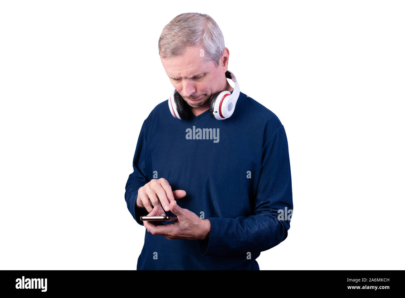 An elderly man is using a telephone. With wireless headphones on the ...