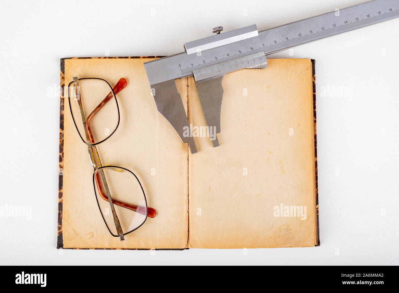 Caliper and old book with glasses on a white table. Workshop ...