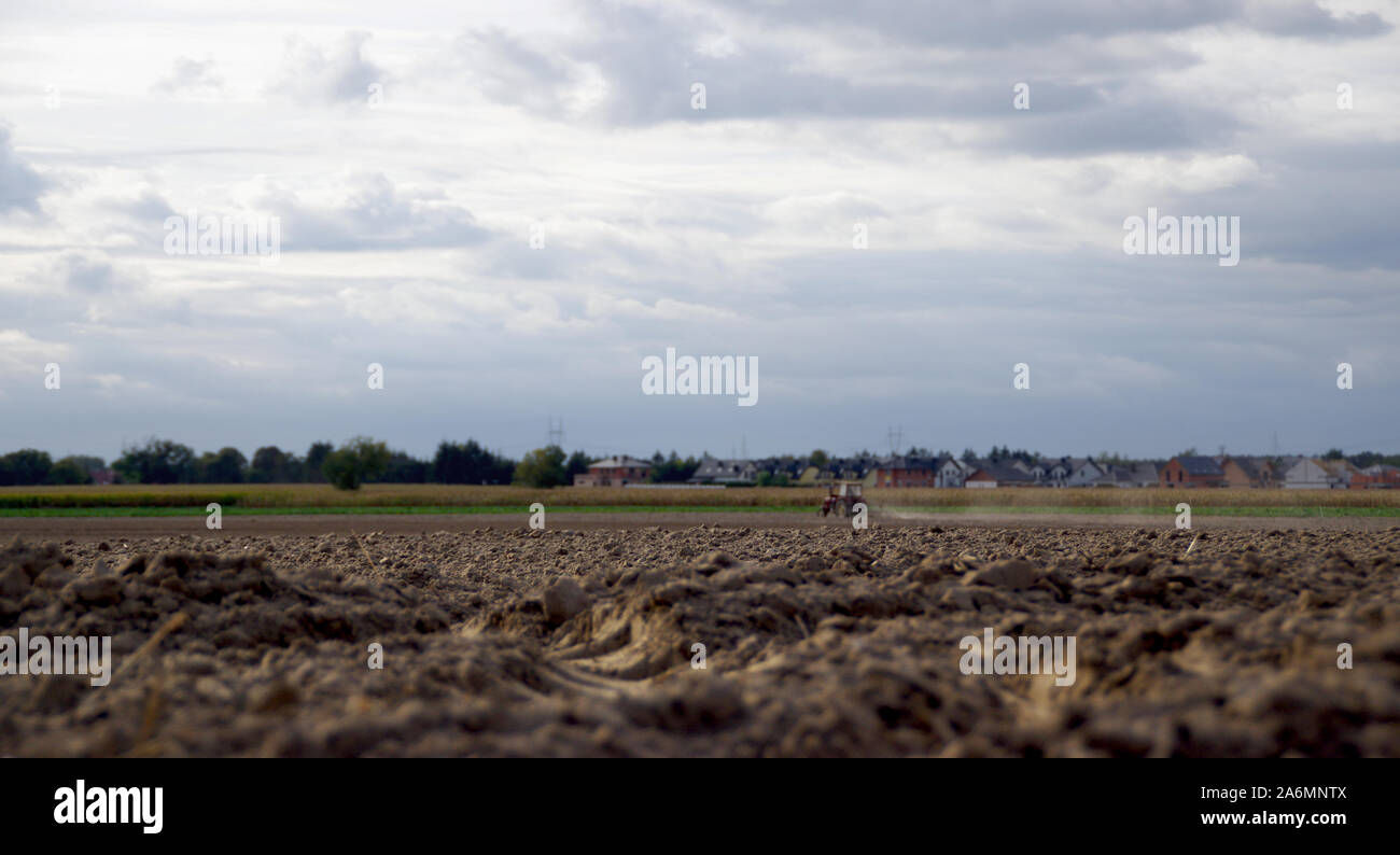 Farmer plowing the dry land with an old tractor in background ...