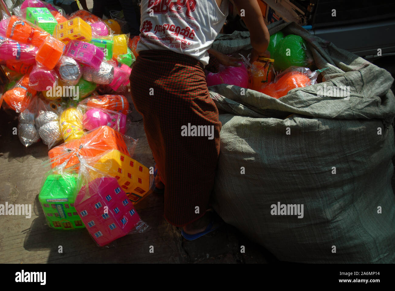 Man putting colourful cheap plastic toys into a large sack, Yangon ...