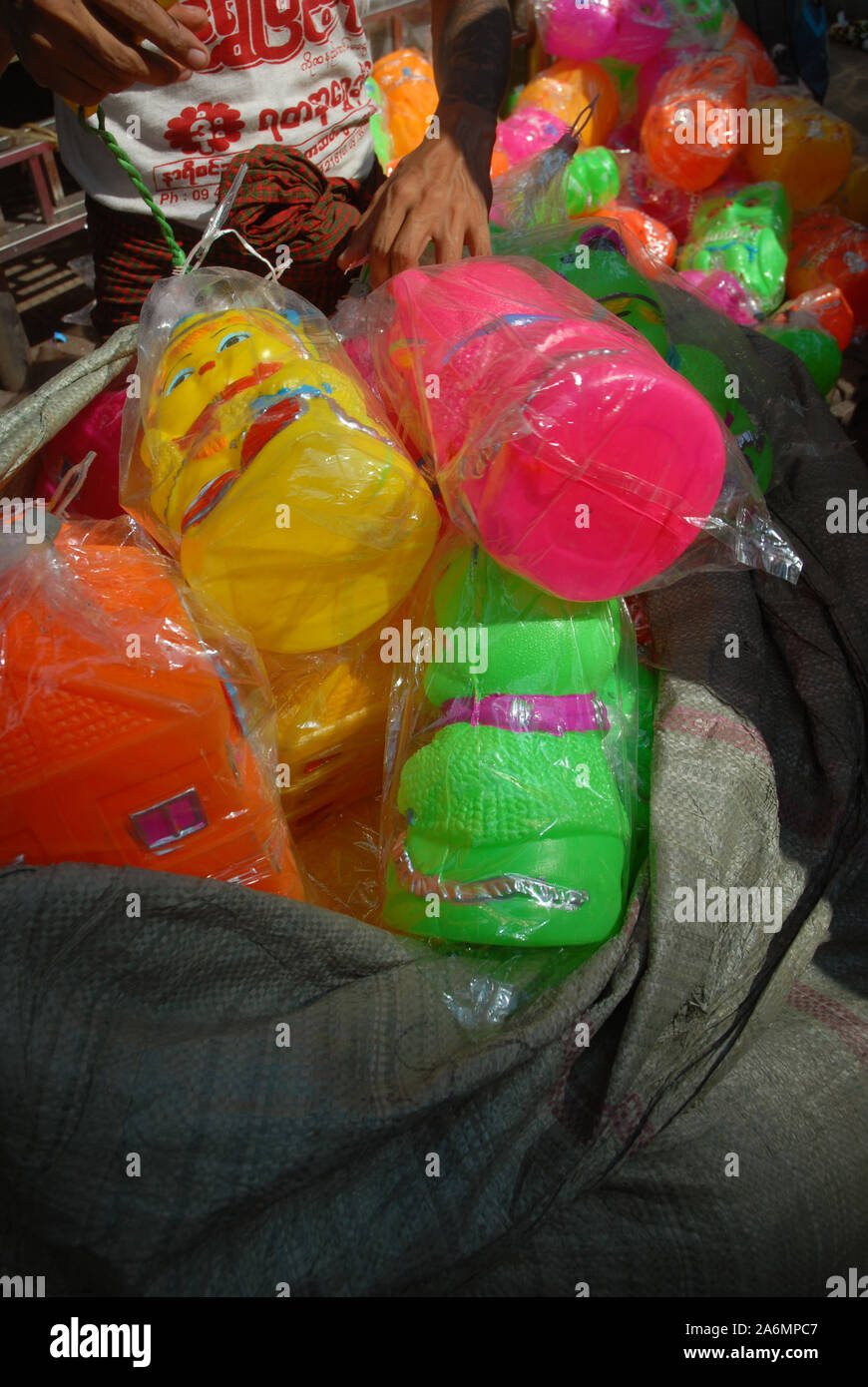 Man putting colourful cheap plastic toys into a large sack, Yangon ...