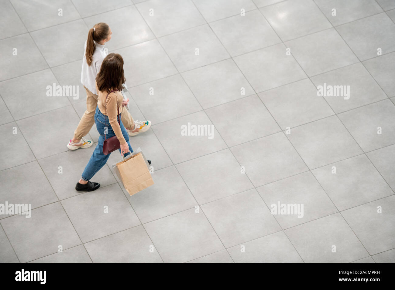 Two female customers in casualwear walking down large contemporary ...