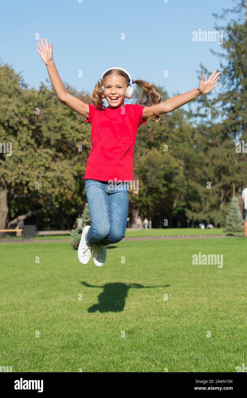 Music of happiness. Happy little child jump high on green grass. Small ...