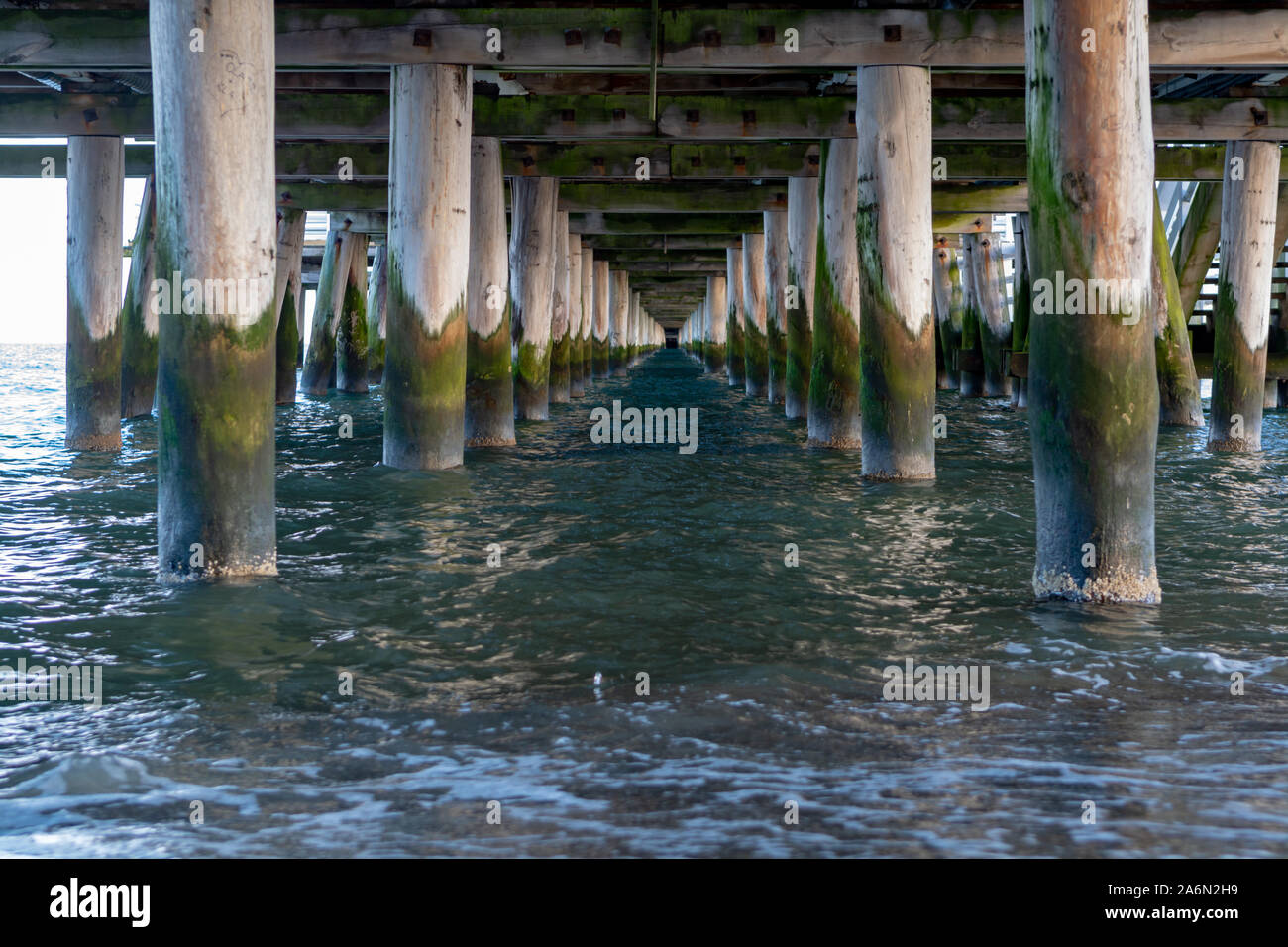 Perspective view on sea or ocean water onder old wooden pier or bridge ...