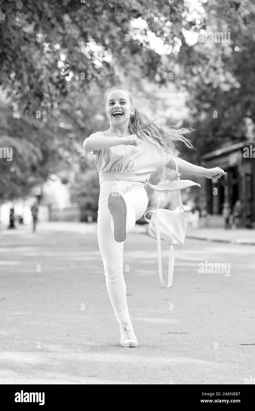 Casual look. Happy small girl marching along street in casual and comfy ...